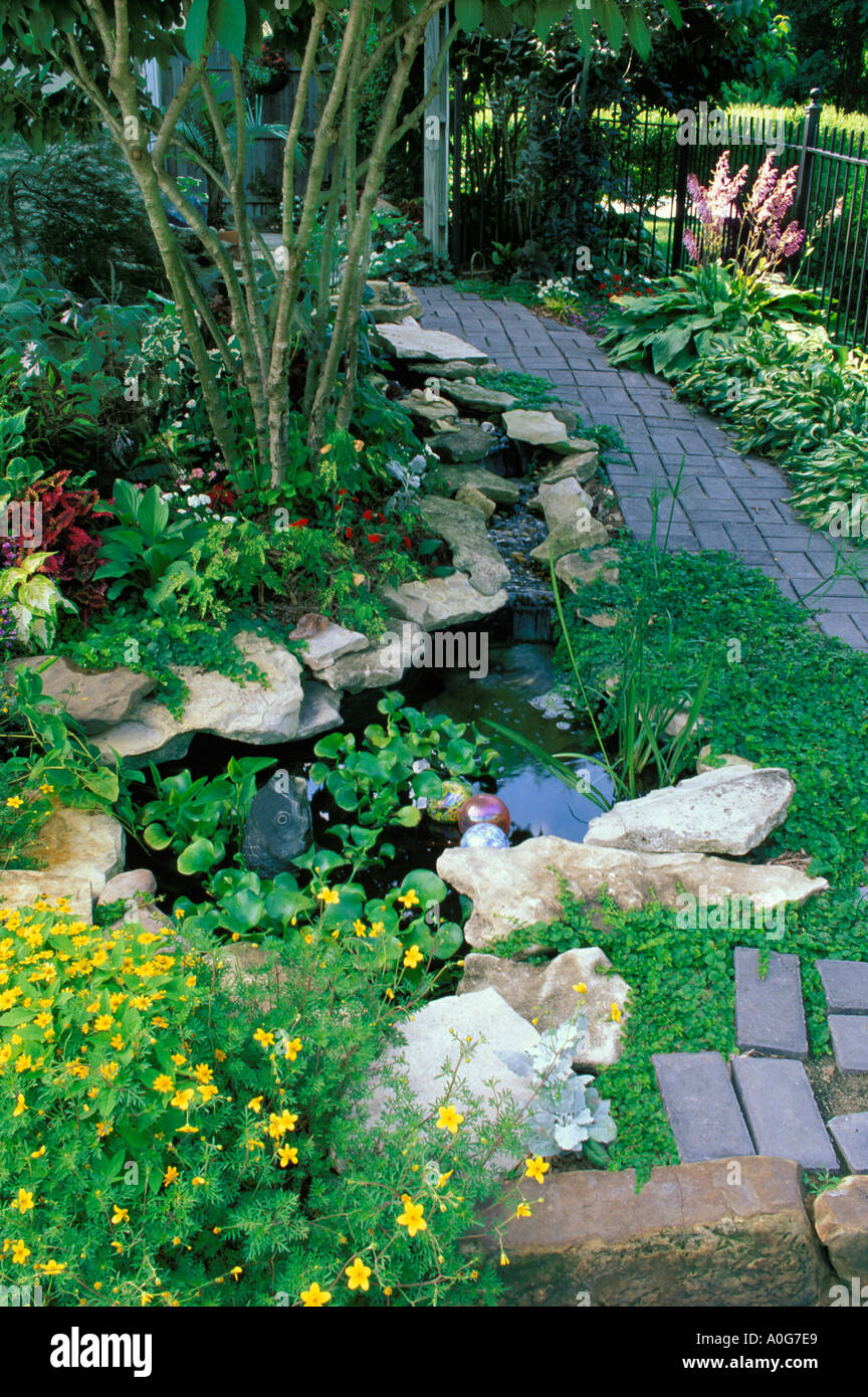 Small decorative fish pool with fountain waterfall in landscaped garden ...