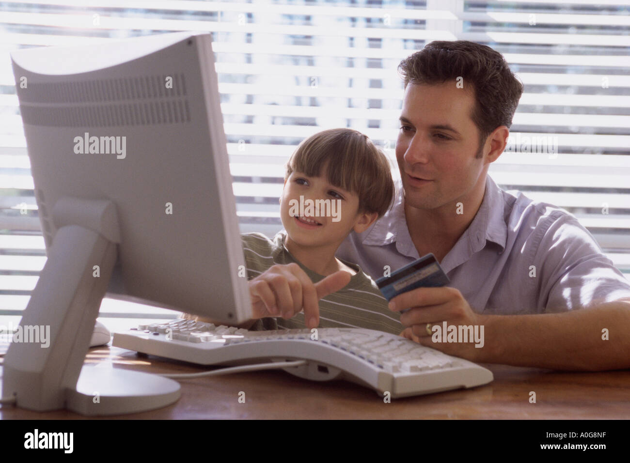 Father and his son sitting in front of a computer Stock Photo - Alamy