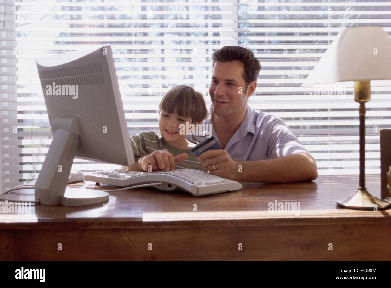 Father and his son sitting in front of a computer Stock Photo - Alamy