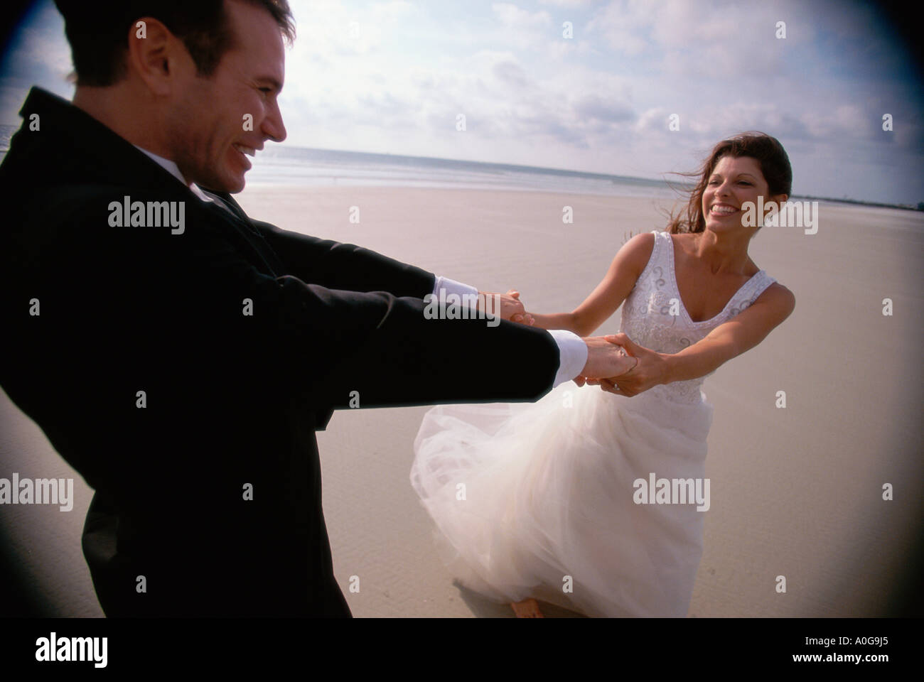 Newlywed couple spinning each other on the beach Stock Photo - Alamy