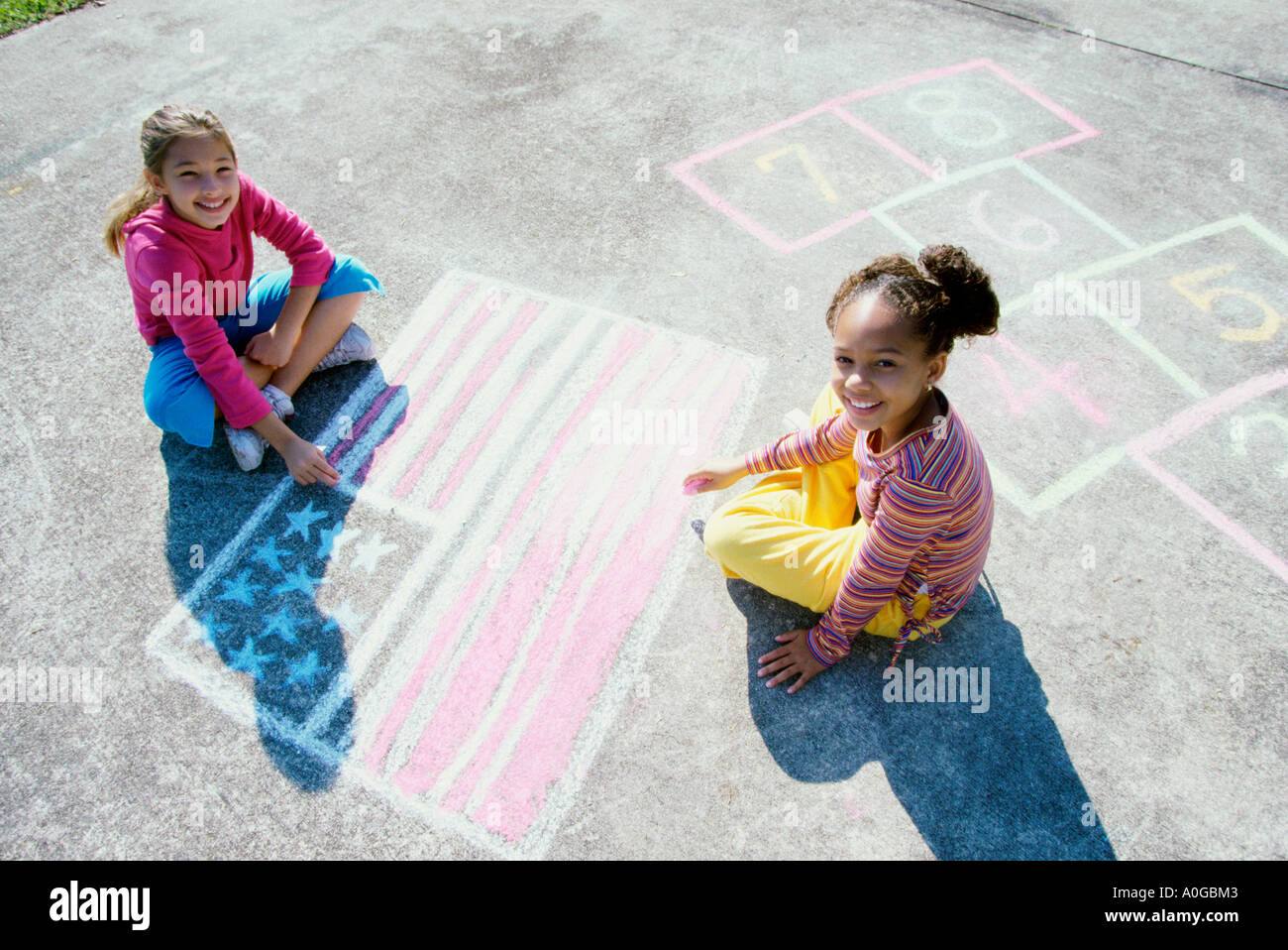 Portrait of two girls drawing on the ground with chalk Stock Photo - Alamy