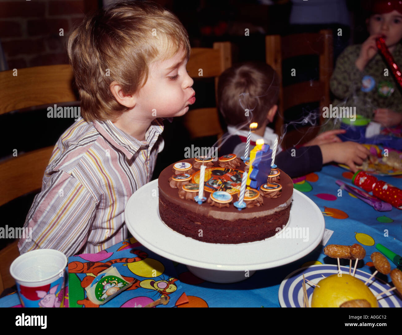 boy blowing candles out at his birthday party Stock Photo - Alamy