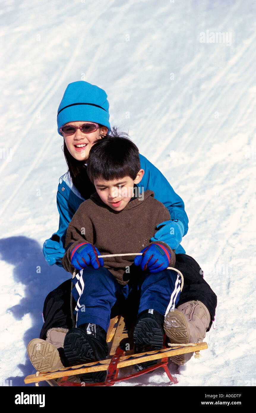 Boy and a girl riding a sled Stock Photo - Alamy