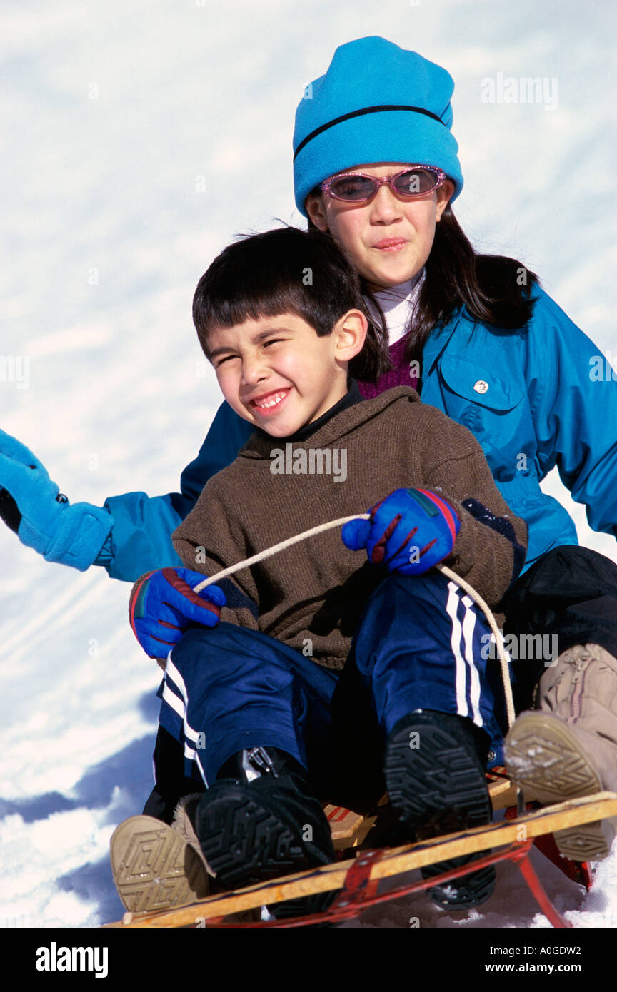 Boy and a girl riding a sled Stock Photo - Alamy