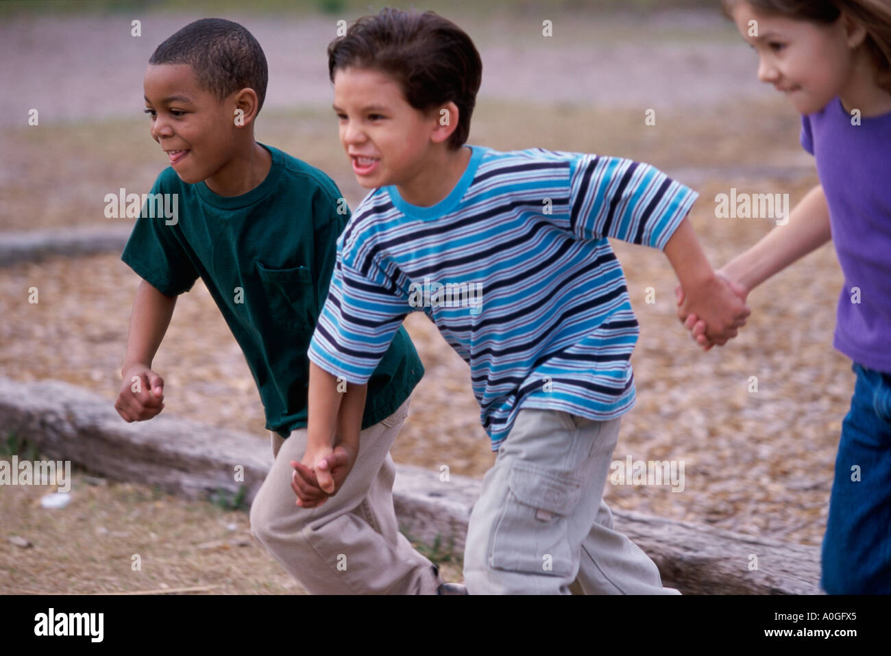 Two boys and a girl running holding hands Stock Photo - Alamy