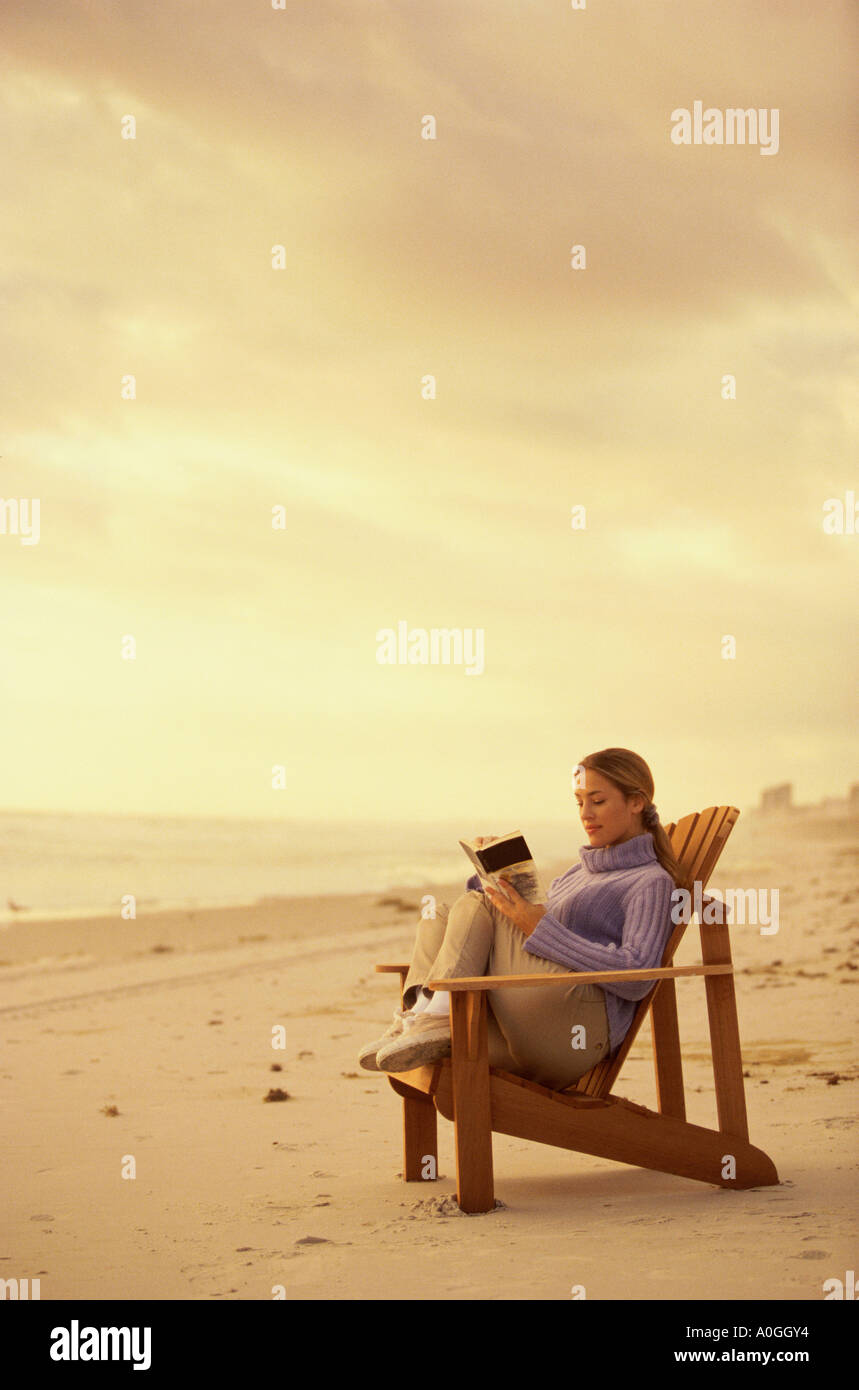 Side profile of a young woman reading a book on the beach Stock Photo ...