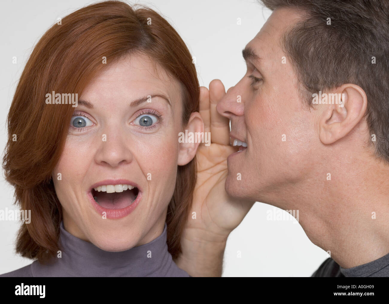 Man telling woman surprising secret Stock Photo - Alamy