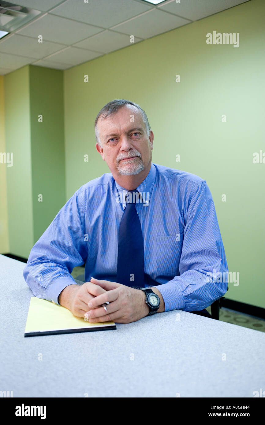 Portrait of a businessman sitting with a notepad in an office Stock ...