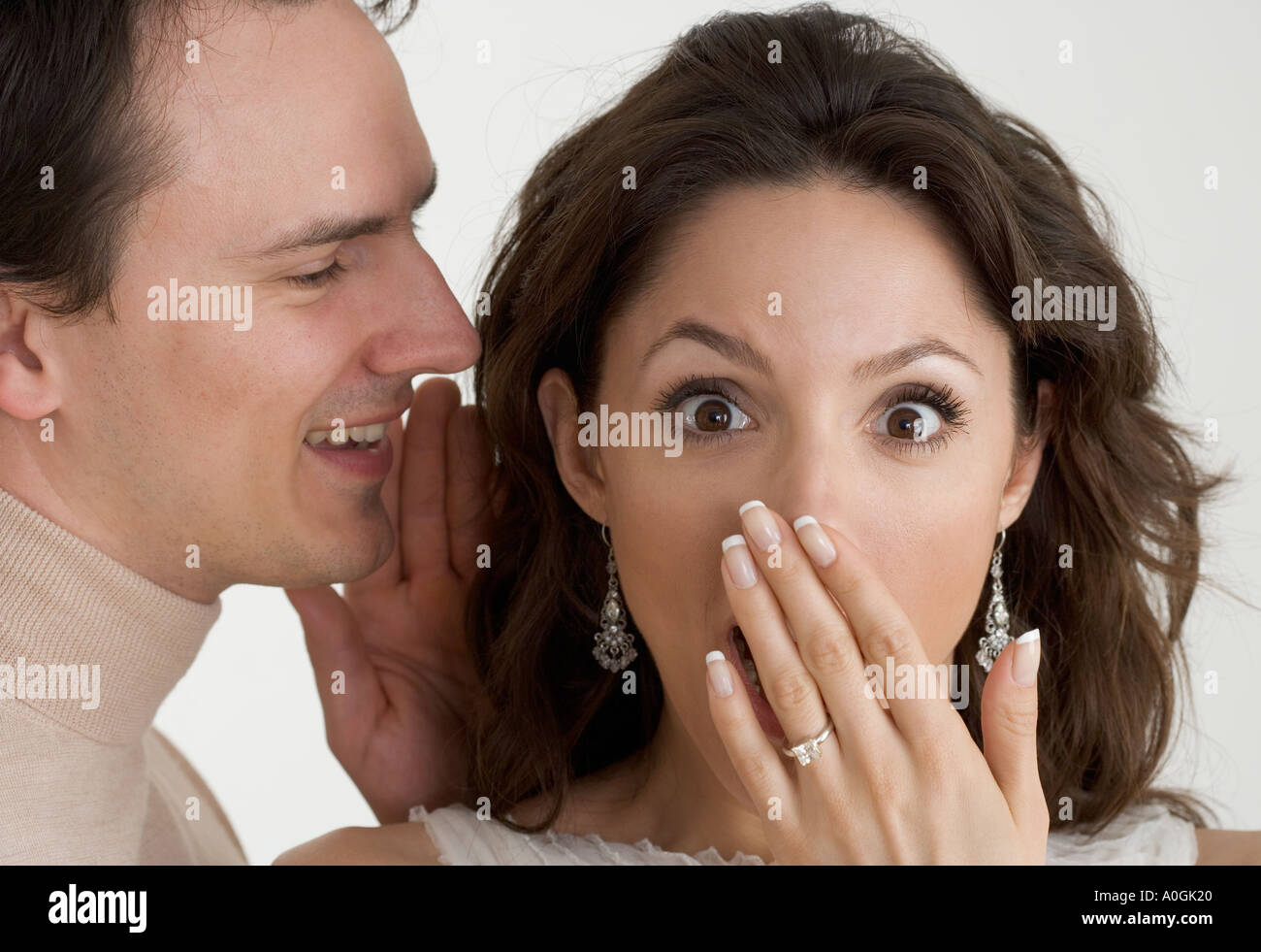 Man telling woman a surprising secret Stock Photo - Alamy