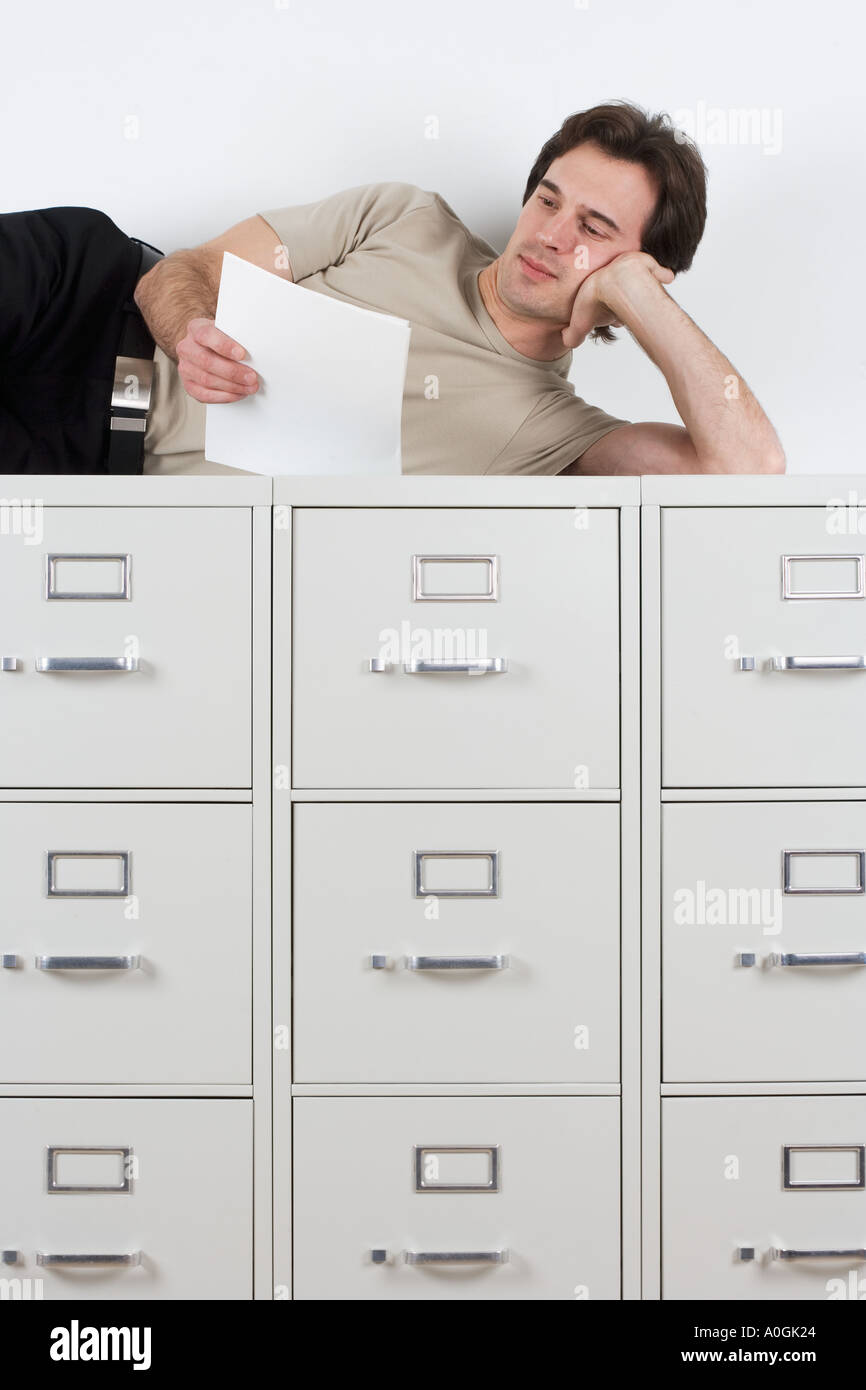 Man reading lying atop file cabinets Stock Photo - Alamy