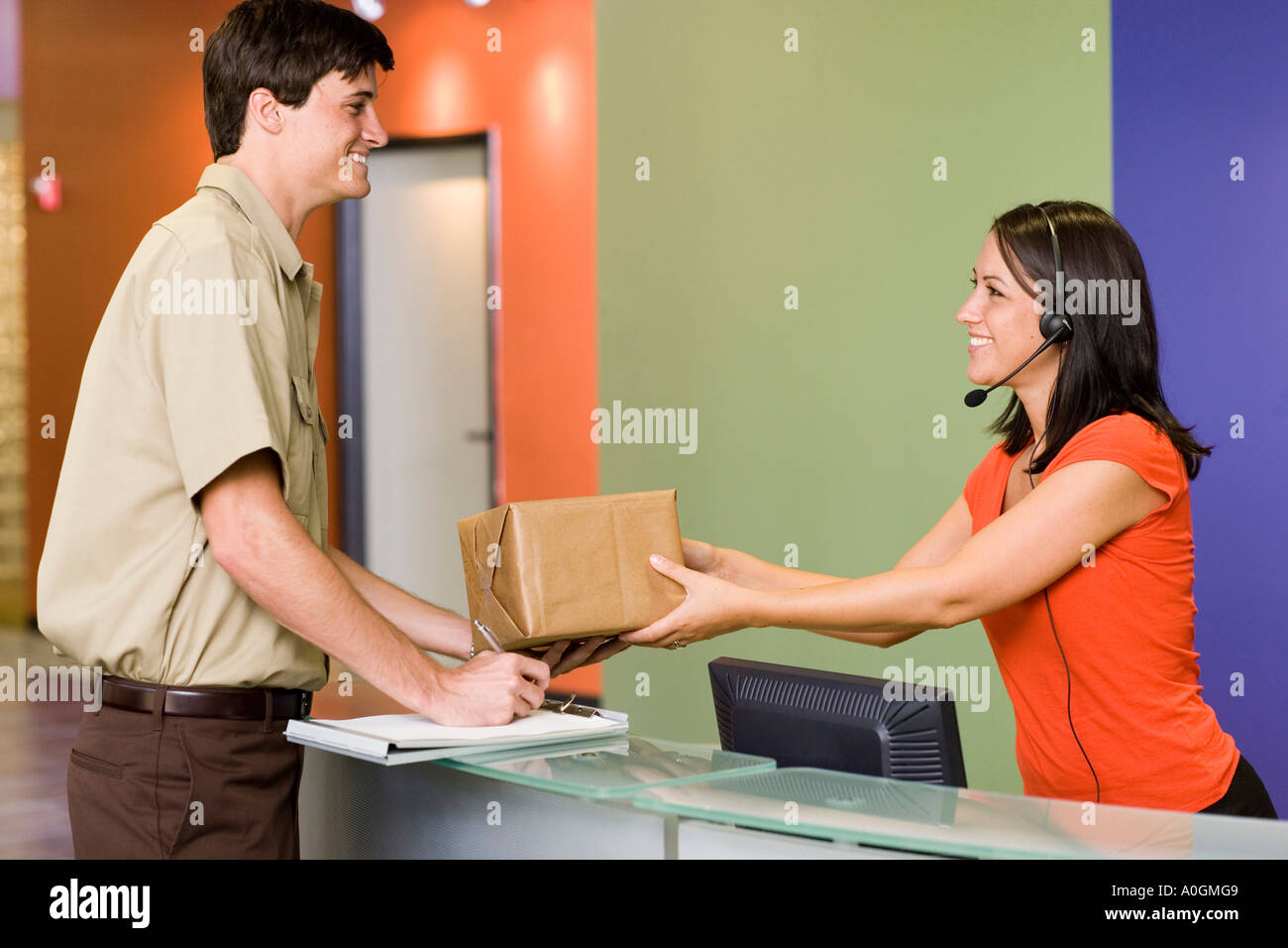 Receptionist receiving a package from a delivery man Stock Photo - Alamy
