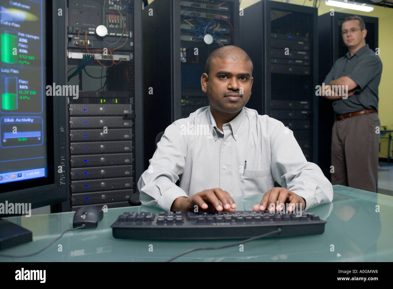 Portrait of a technician using a computer with another technician ...