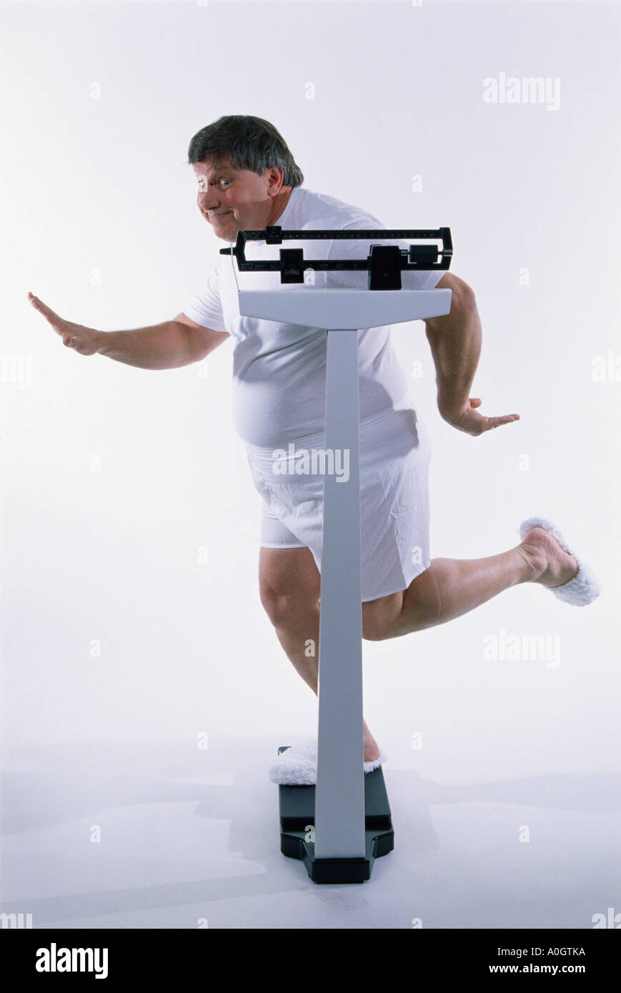 Portrait of a man making a funny face standing on a scale Stock Photo ...