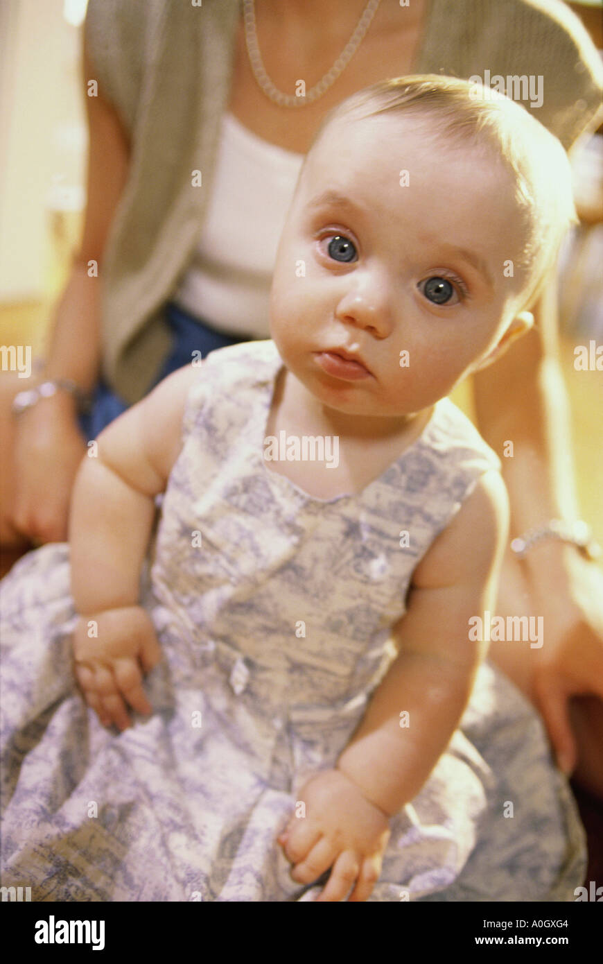 Portrait of a baby girl sitting with her mother behind her Stock Photo ...