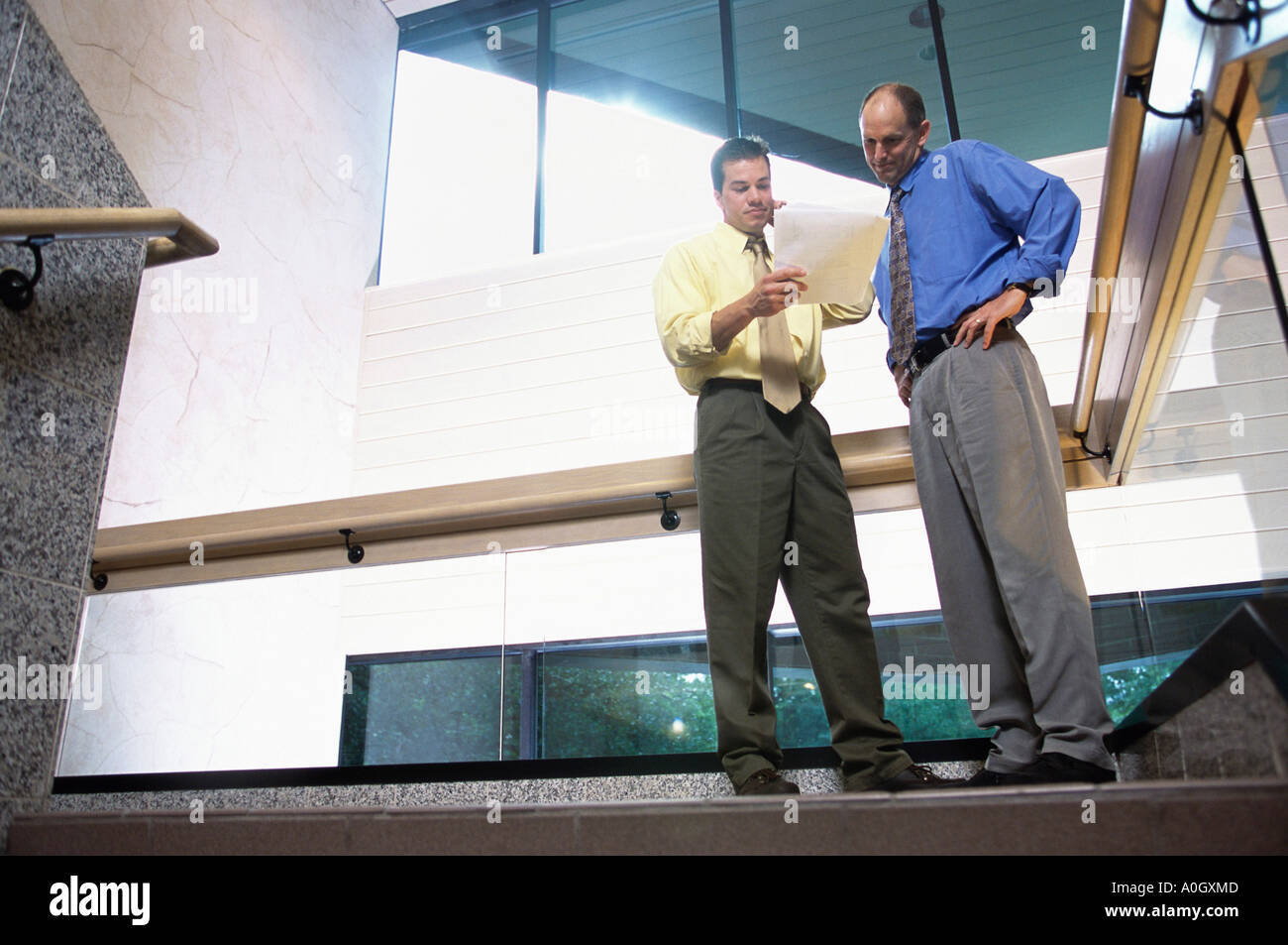 Low angle view of two businessmen discussing on the top of a staircase ...