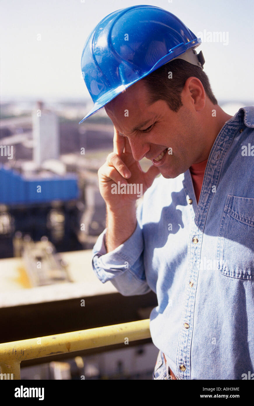 Construction worker touching his head looking down Stock Photo - Alamy
