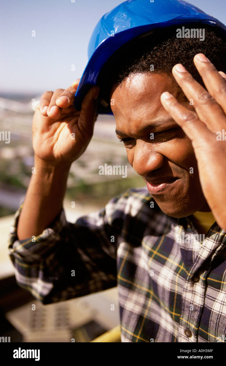 Construction worker touching his head and removing his hardhat Stock ...