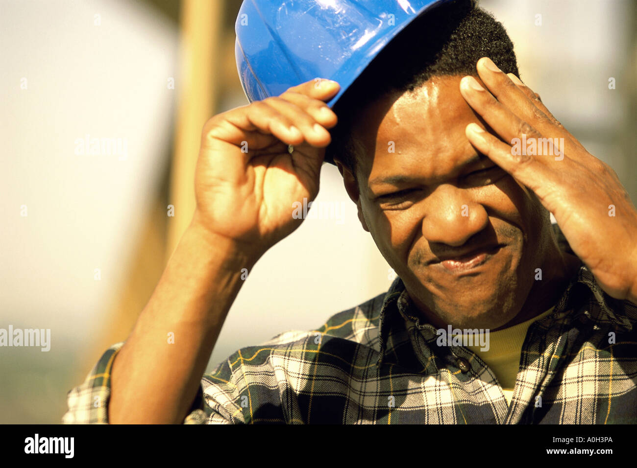 Close-up of a construction worker touching his head and removing his ...