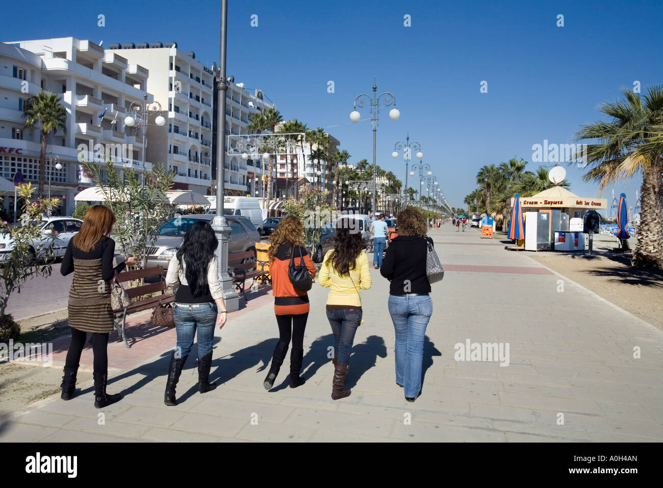 A BACK VIEW OF LOCAL GIRLS WALKING ALONG THE LARNAKA TOWN SEAFRONT IN ...