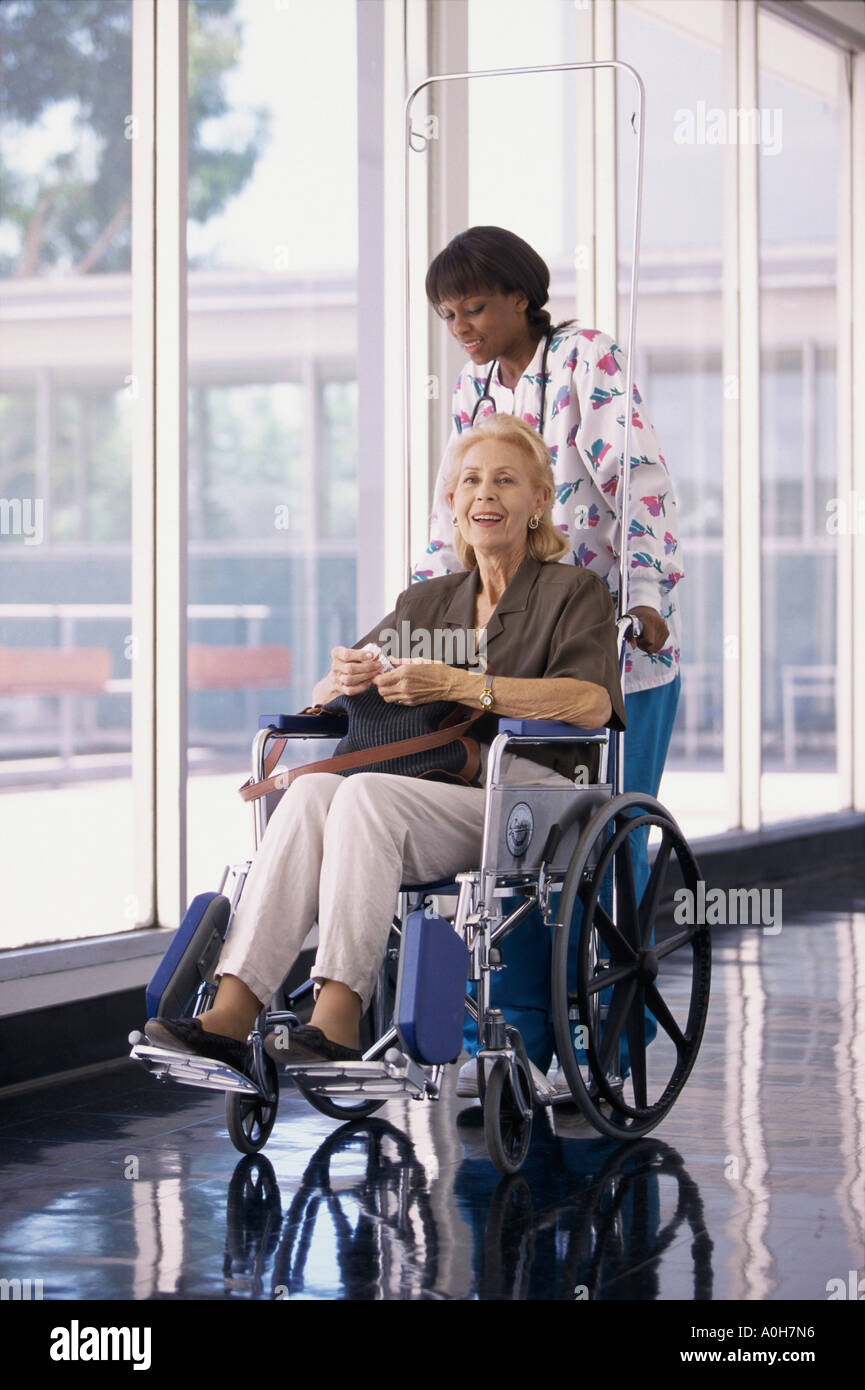 Female nurse pushing a female patient in a wheelchair Stock Photo - Alamy