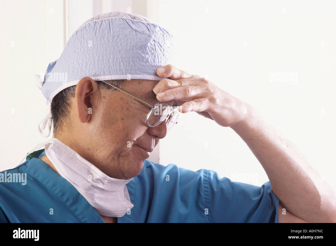 Side profile of a male doctor with his hand on his head Stock Photo - Alamy