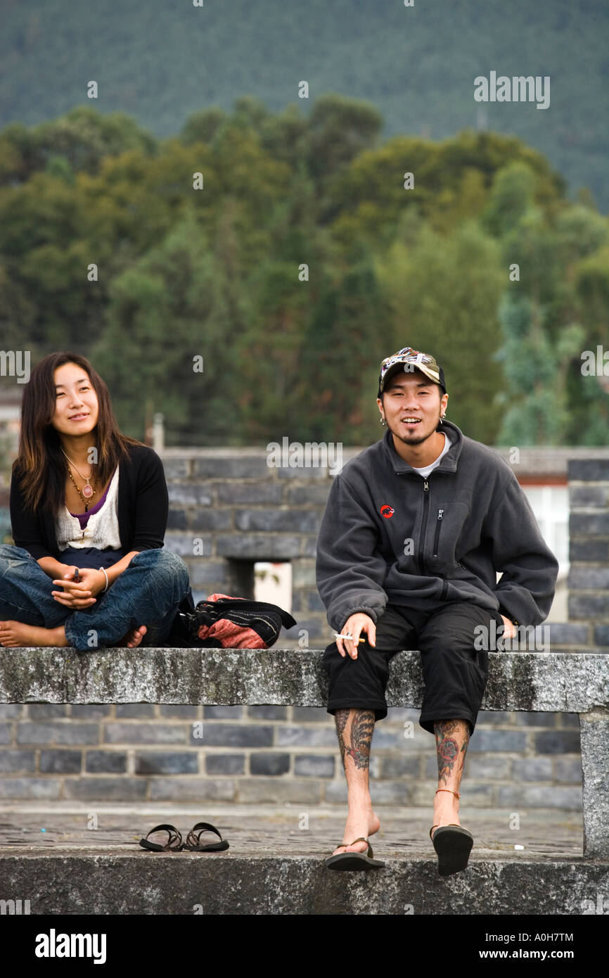 Two young Chinese adults relaxing on park bench, Dali, Yunnan, China ...