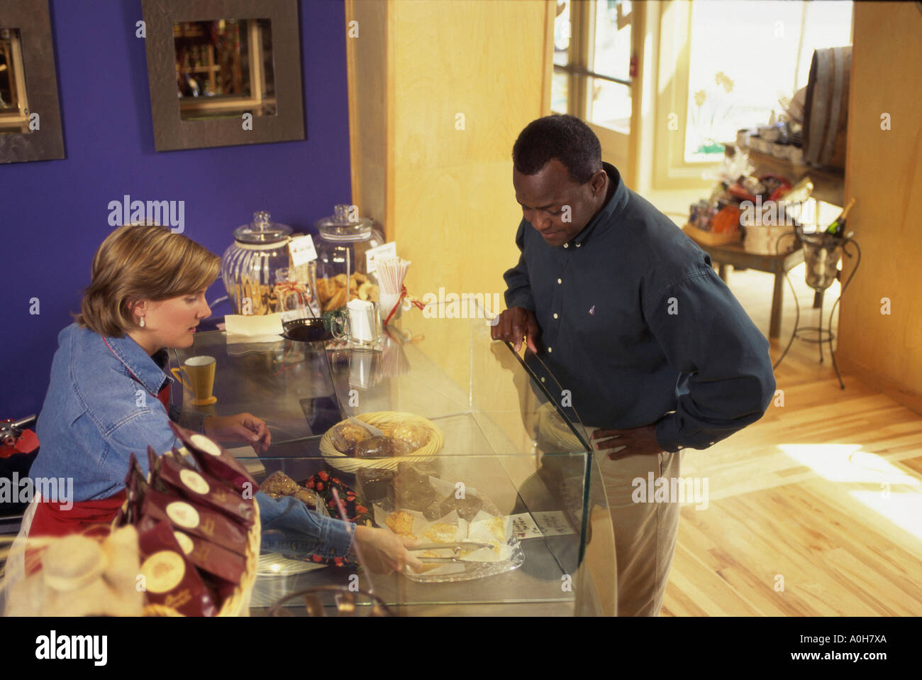 Woman standing behind a counter serving a man sweets Stock Photo - Alamy