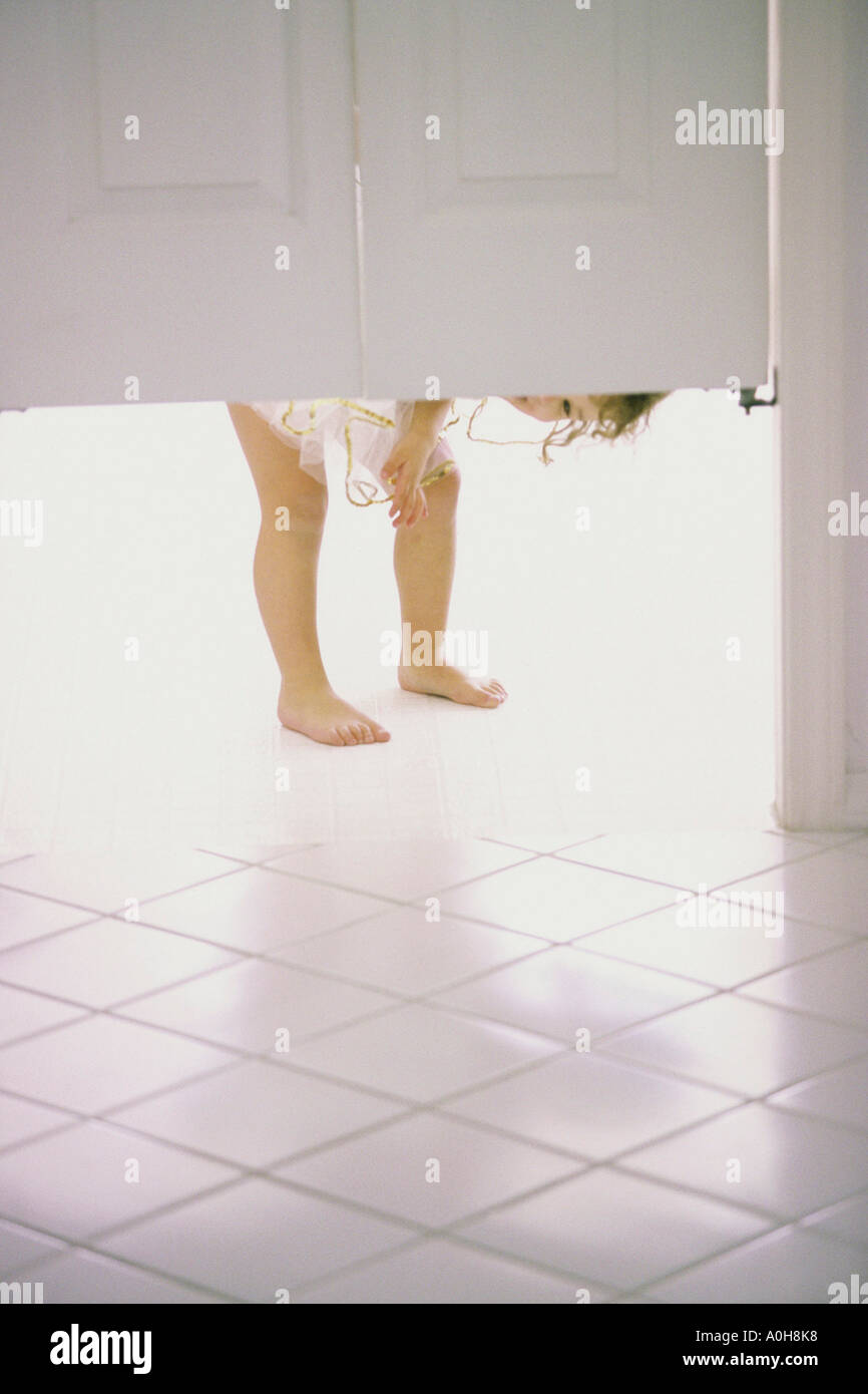 Girl peeking from under a swinging door Stock Photo - Alamy