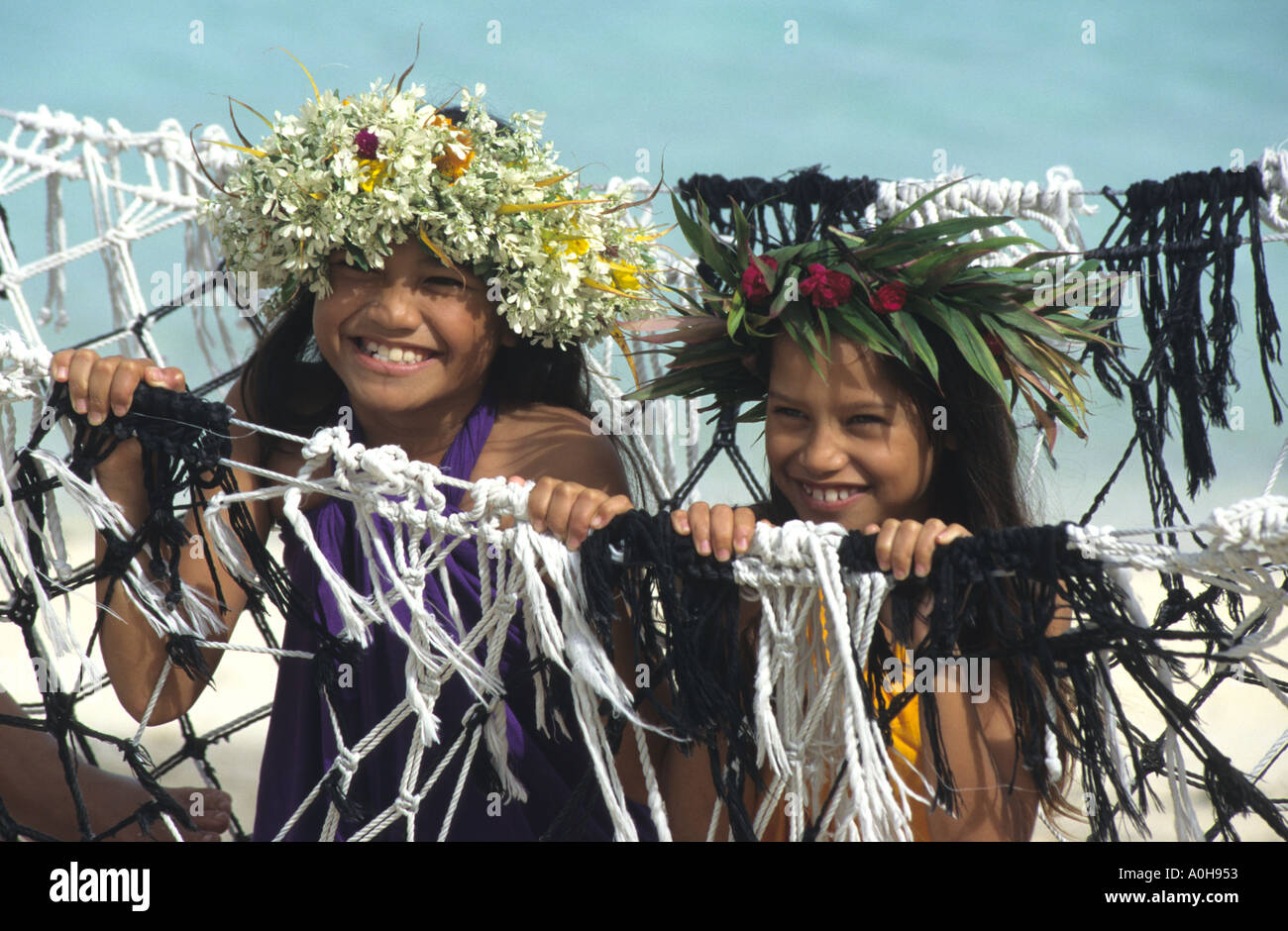 Two young Cook Island girls playing in a hammock and laughing Stock ...