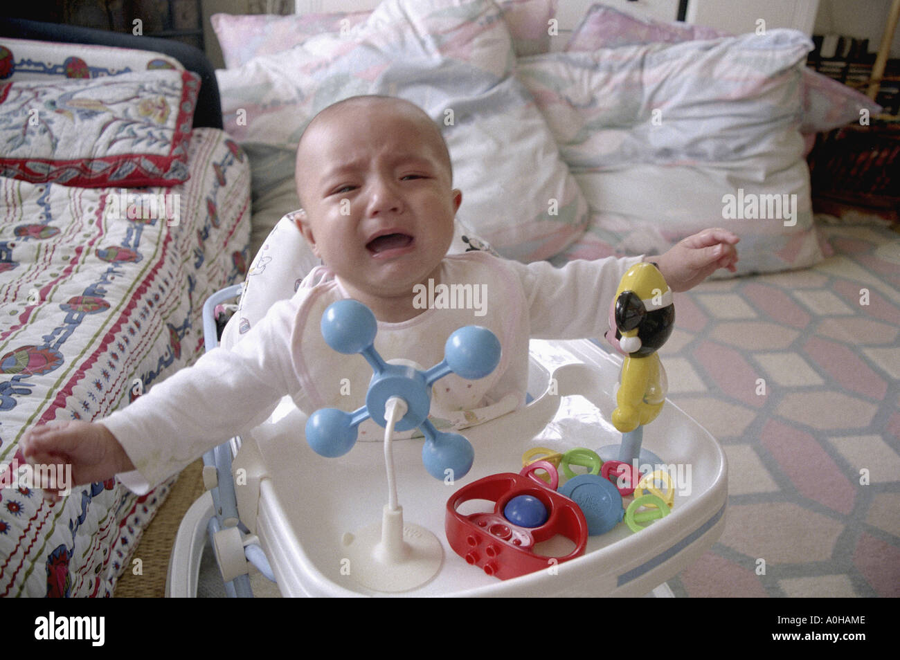 Baby crying in a walker Stock Photo - Alamy
