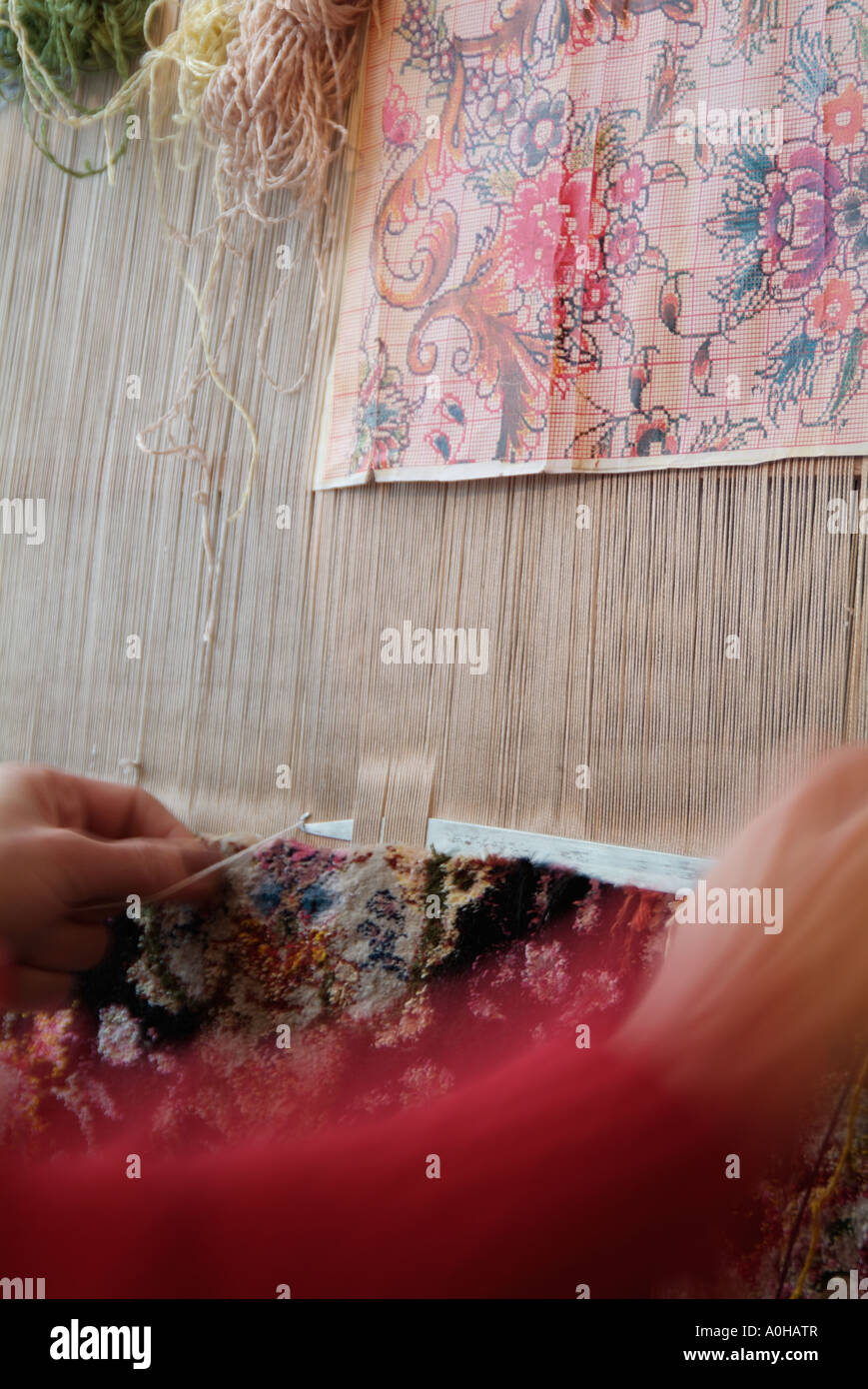 Skilled weaver weaving woman carpet on loom traditional dress knot tie ...