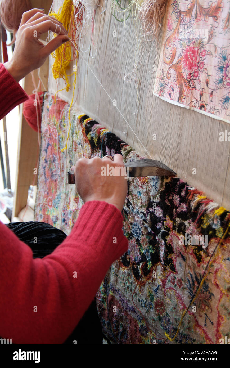 Skilled weaver weaving woman carpet on loom traditional dress knot tie ...