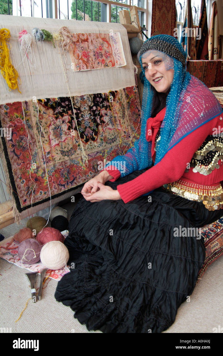 Skilled weaver weaving woman carpet on loom traditional dress knot tie ...