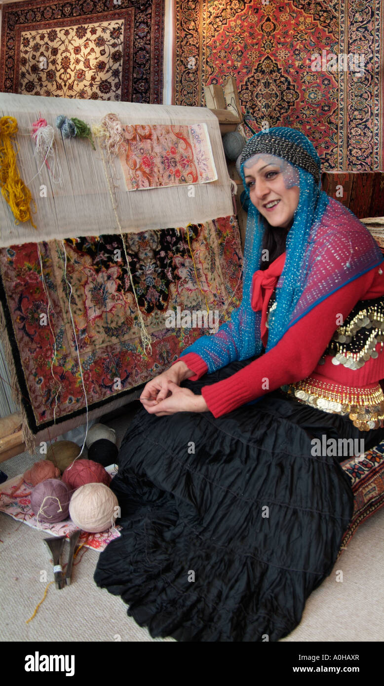 Skilled weaver weaving woman carpet on loom traditional dress knot tie ...