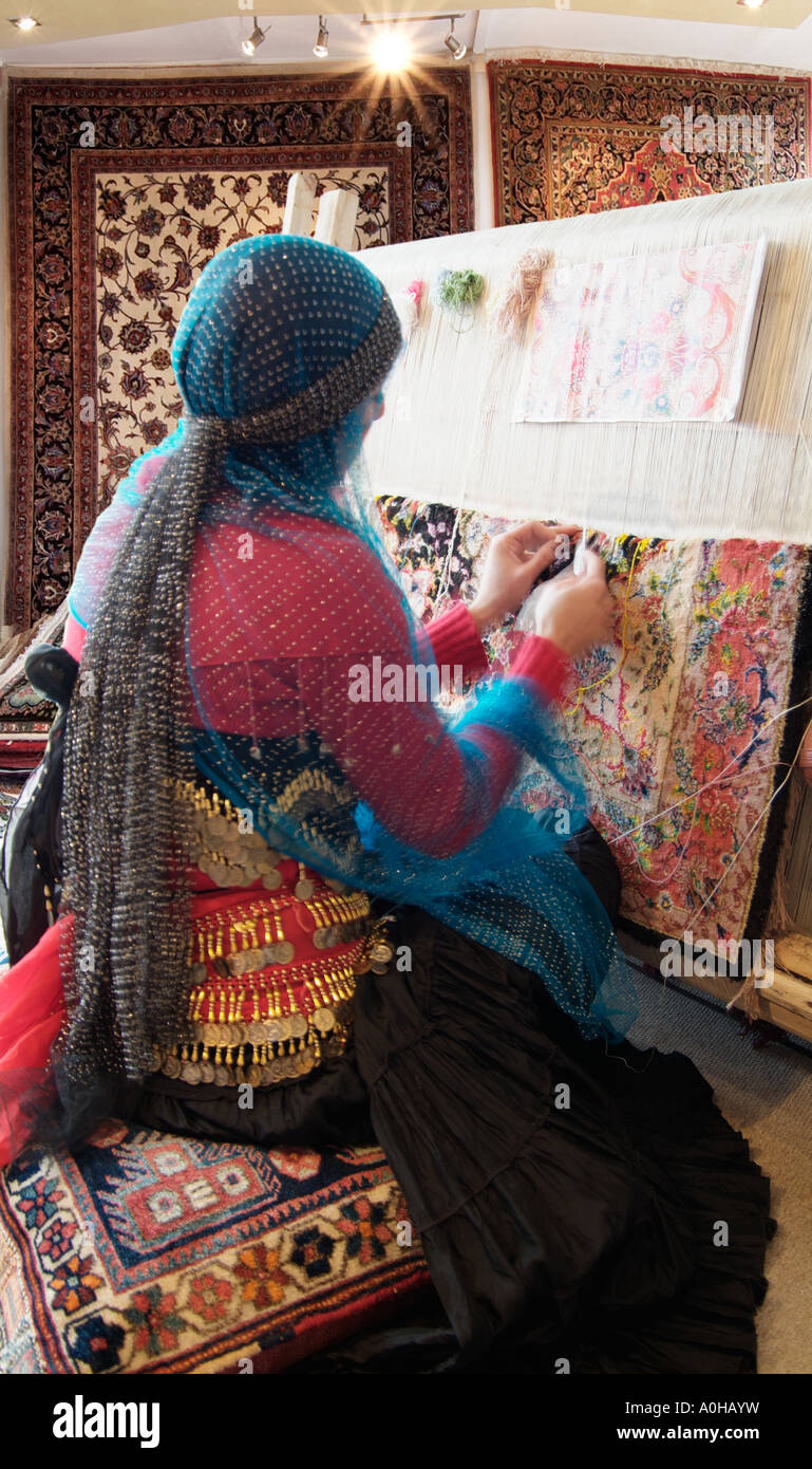 Skilled weaver weaving woman carpet on loom traditional dress knot tie ...