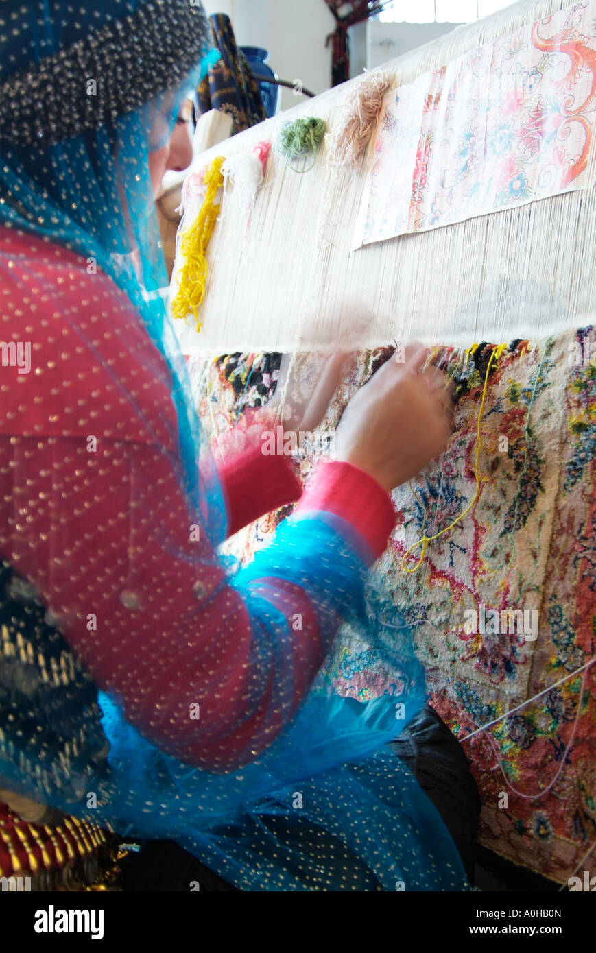 Skilled weaver weaving woman carpet on loom traditional dress knot tie ...