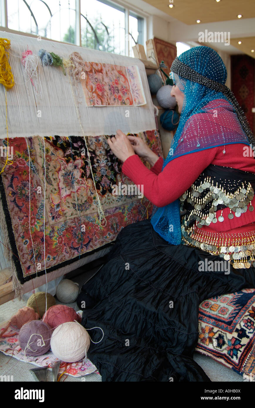 Skilled weaver weaving woman carpet on loom traditional dress knot tie ...