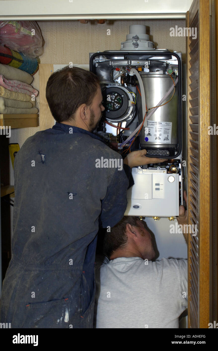 Two adult male workers installing a new Combi boiler into a house Stock ...