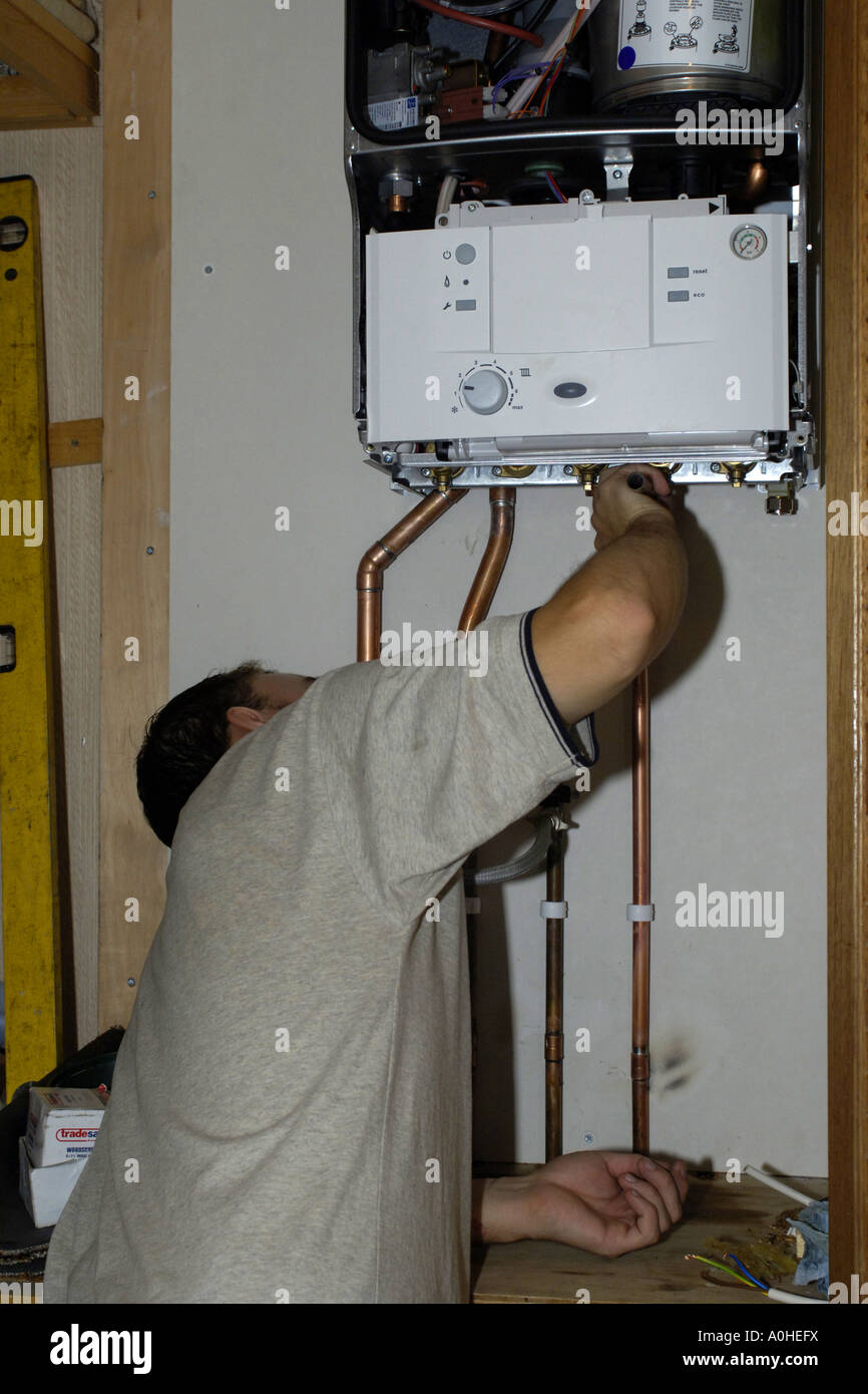 Adult male worker installing new pipework using a gas burner to solder the joints on a new ...