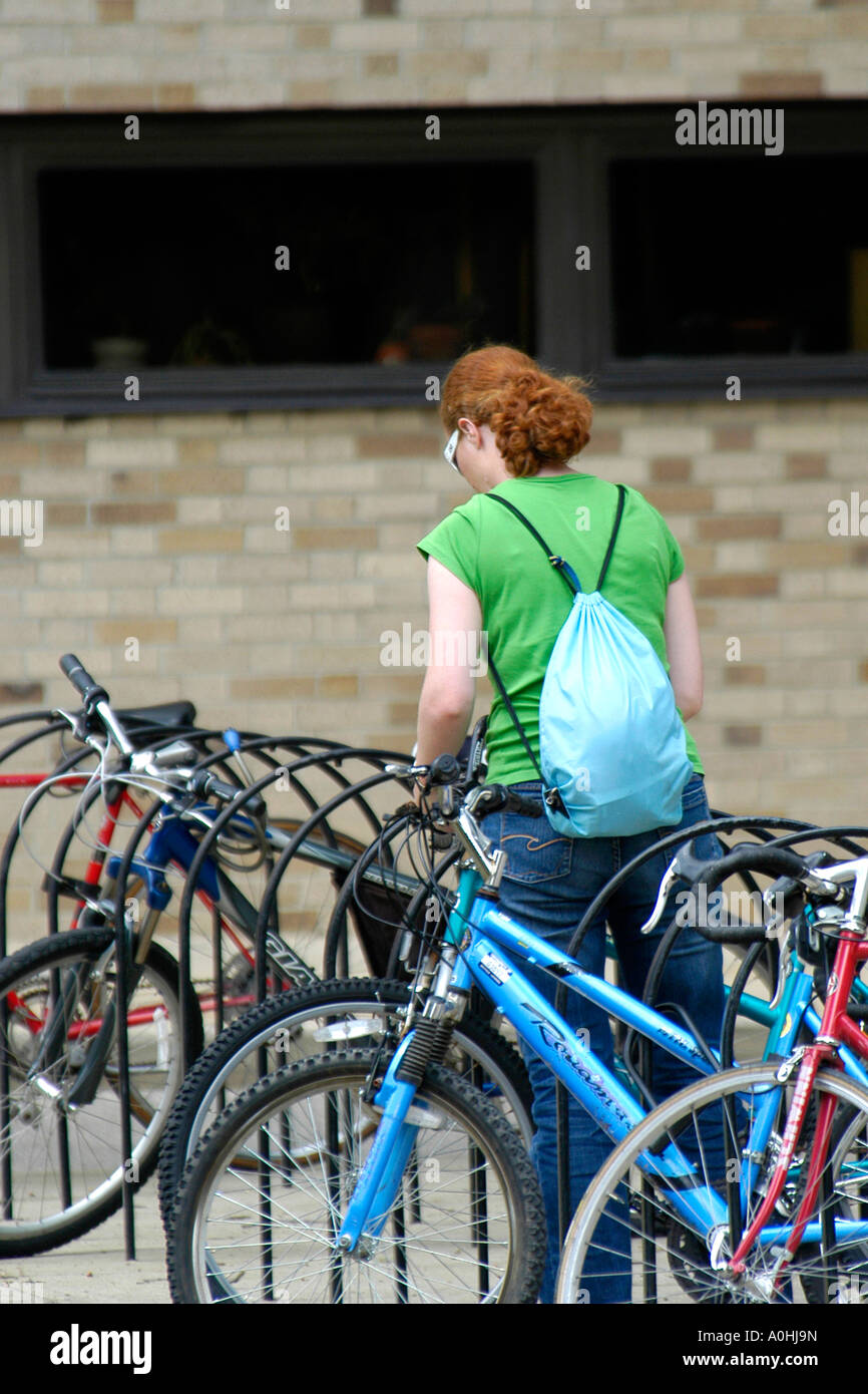 Female student locking her bicycle into a bike rack at the University ...