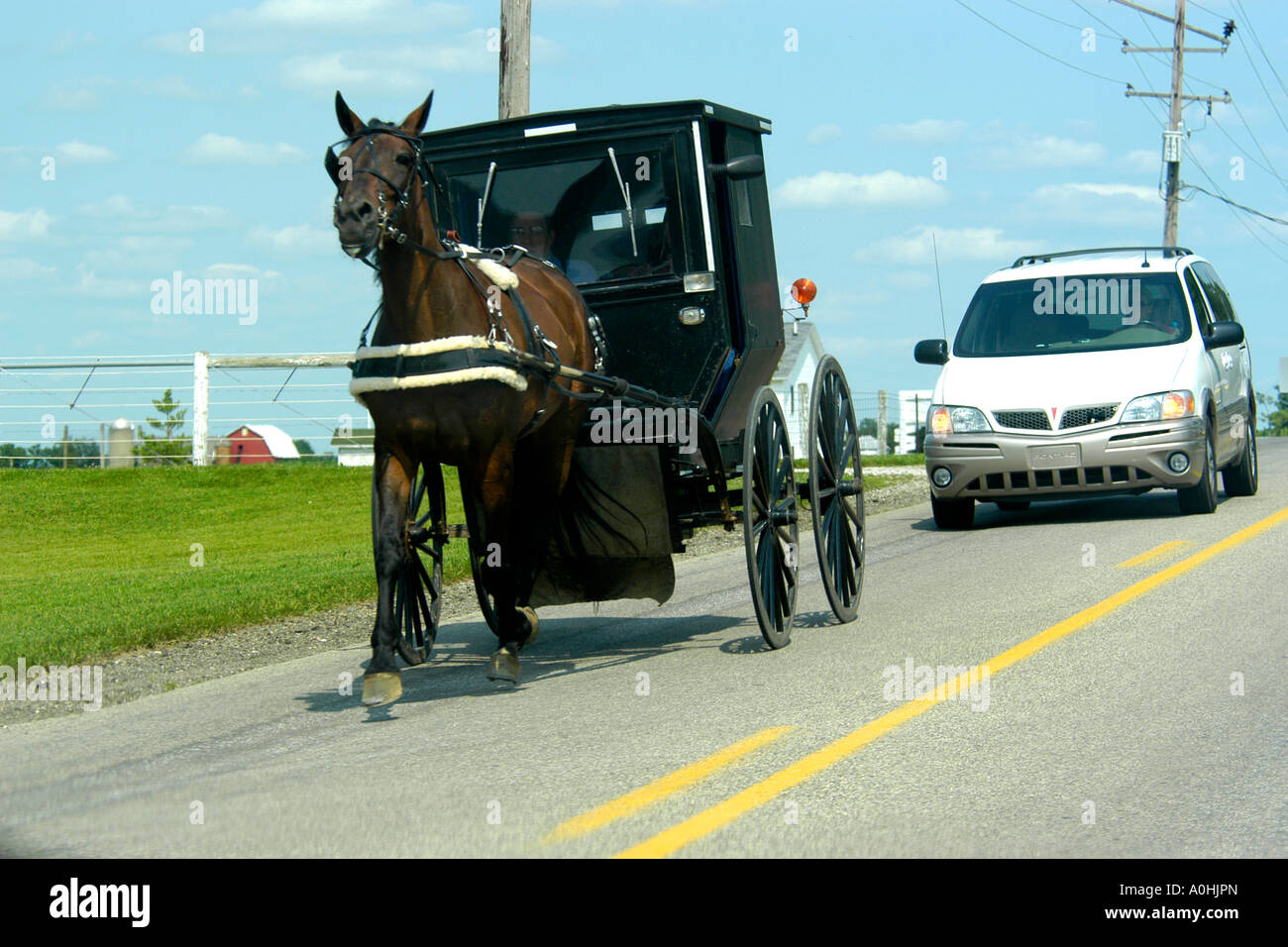 Amish family riding in a horse drawn buggy along the main highway in ...