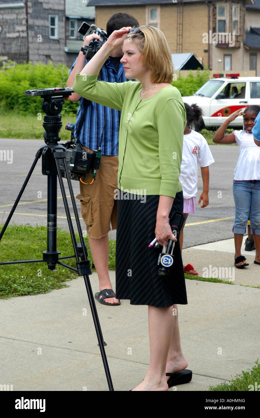 A woman TV News Reporter stands looking shocked at a Fire in Toledo ...