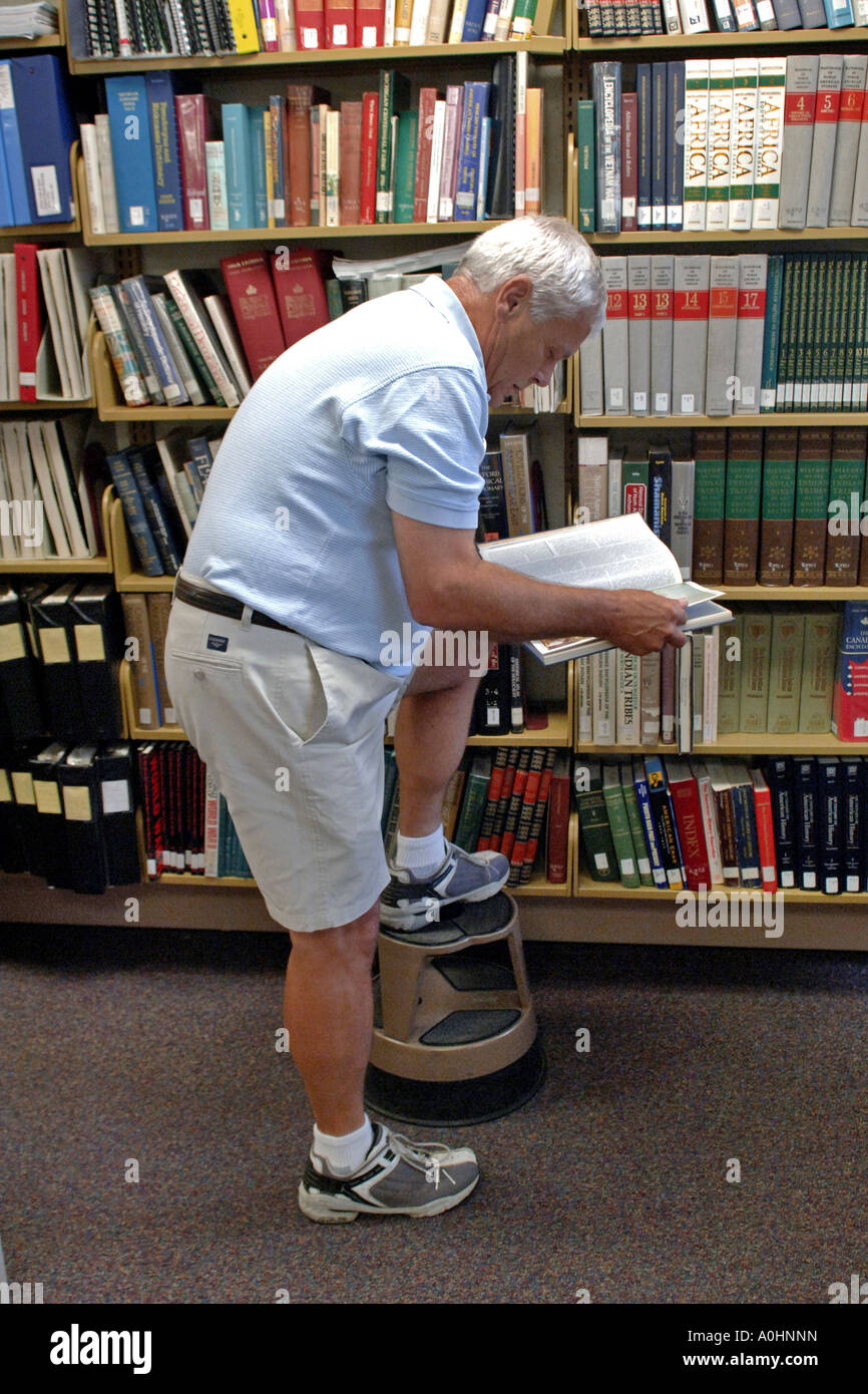 An adult male searching for a reference book in a Library Stock Photo ...