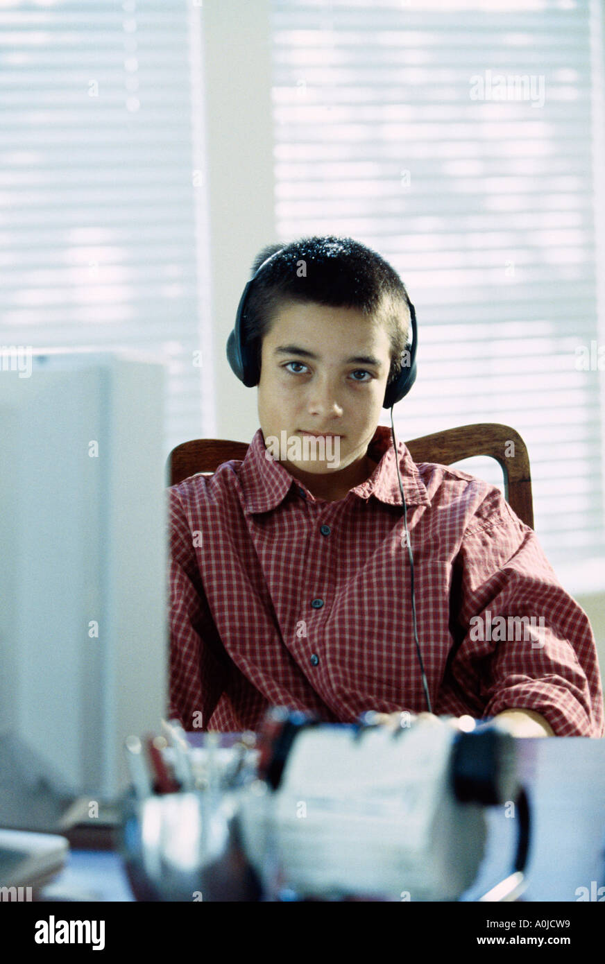 Portrait of a teenage boy sitting in front of a computer monitor Stock ...