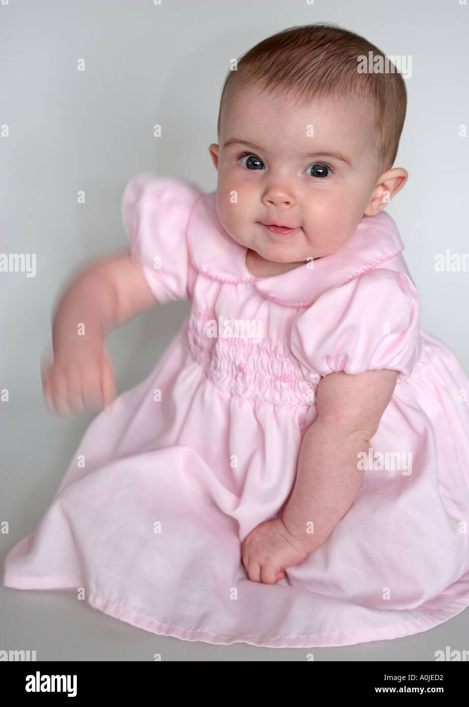 Baby girl in sitting position lifting her arm up ready to move forwards ...