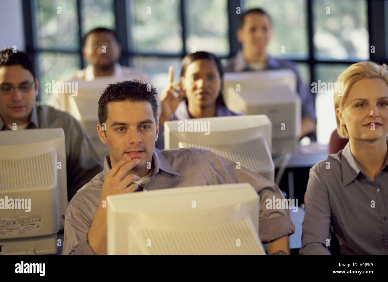 Business executives sitting in front of computer monitors in an office ...
