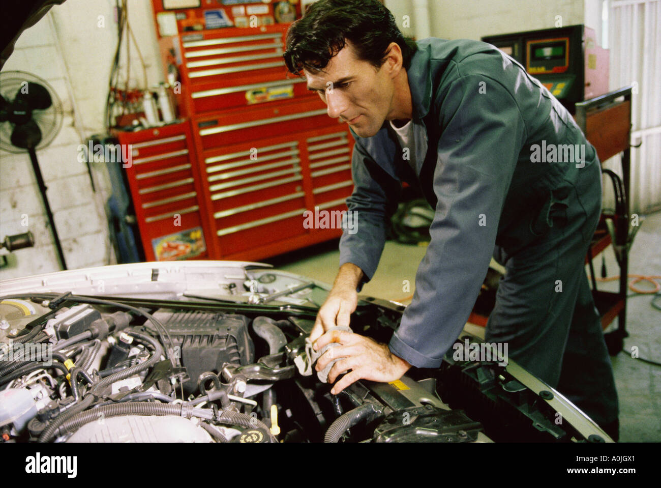 Auto mechanic working over the engine bay of a car Stock Photo - Alamy