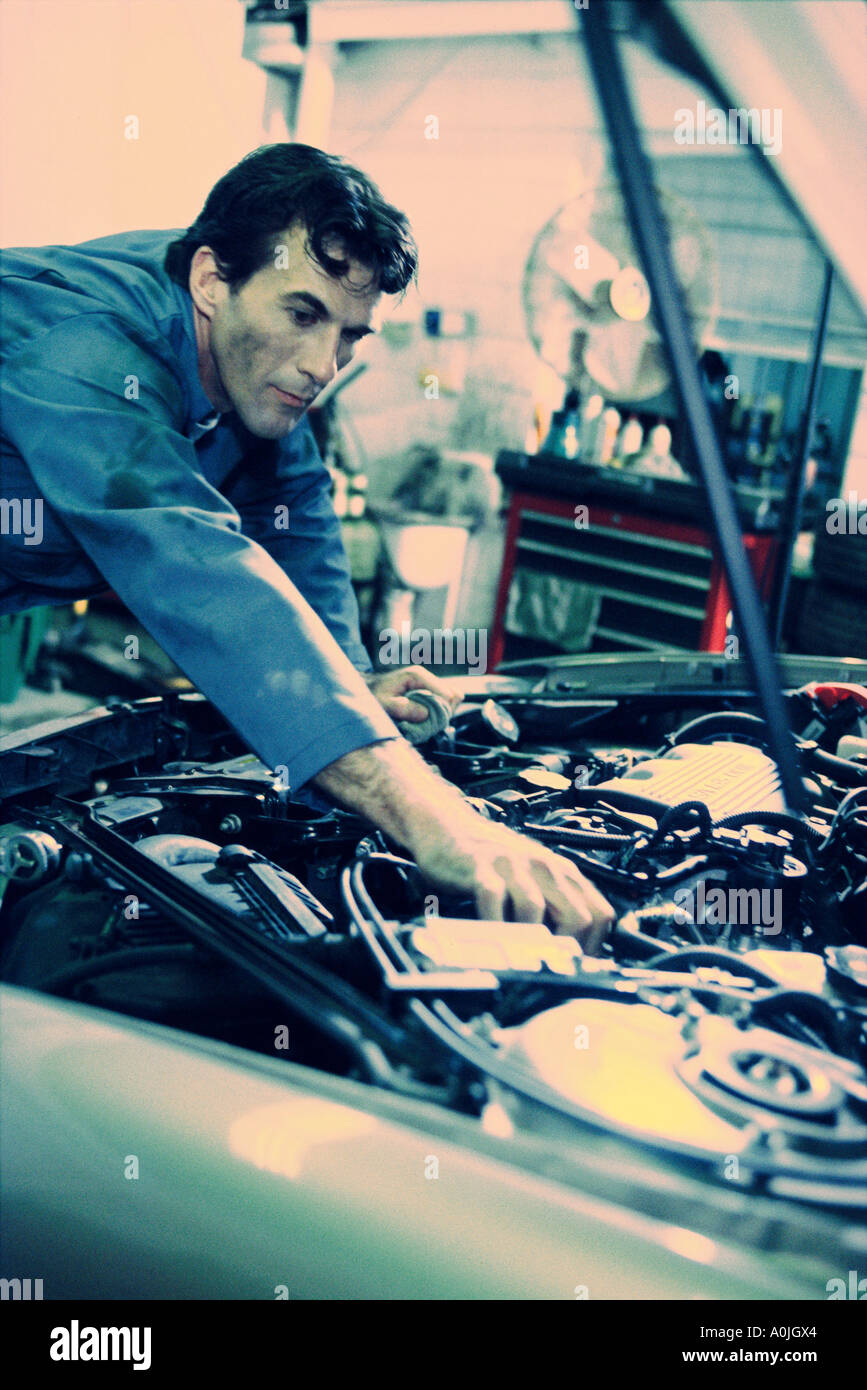 Auto mechanic working over the engine bay of a car Stock Photo - Alamy