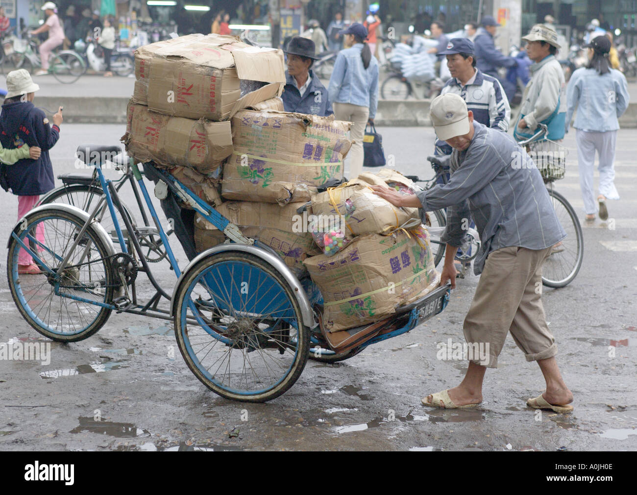 A pedicab driver secures a large load on a street in Hue Vietnam Stock ...