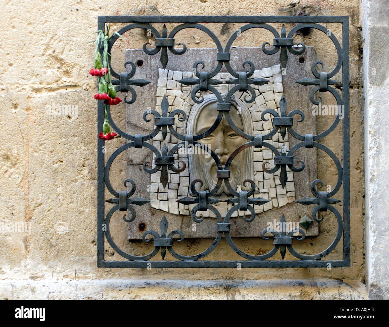Image of Jesus behind iron grill with red roses in Alicante old town ...
